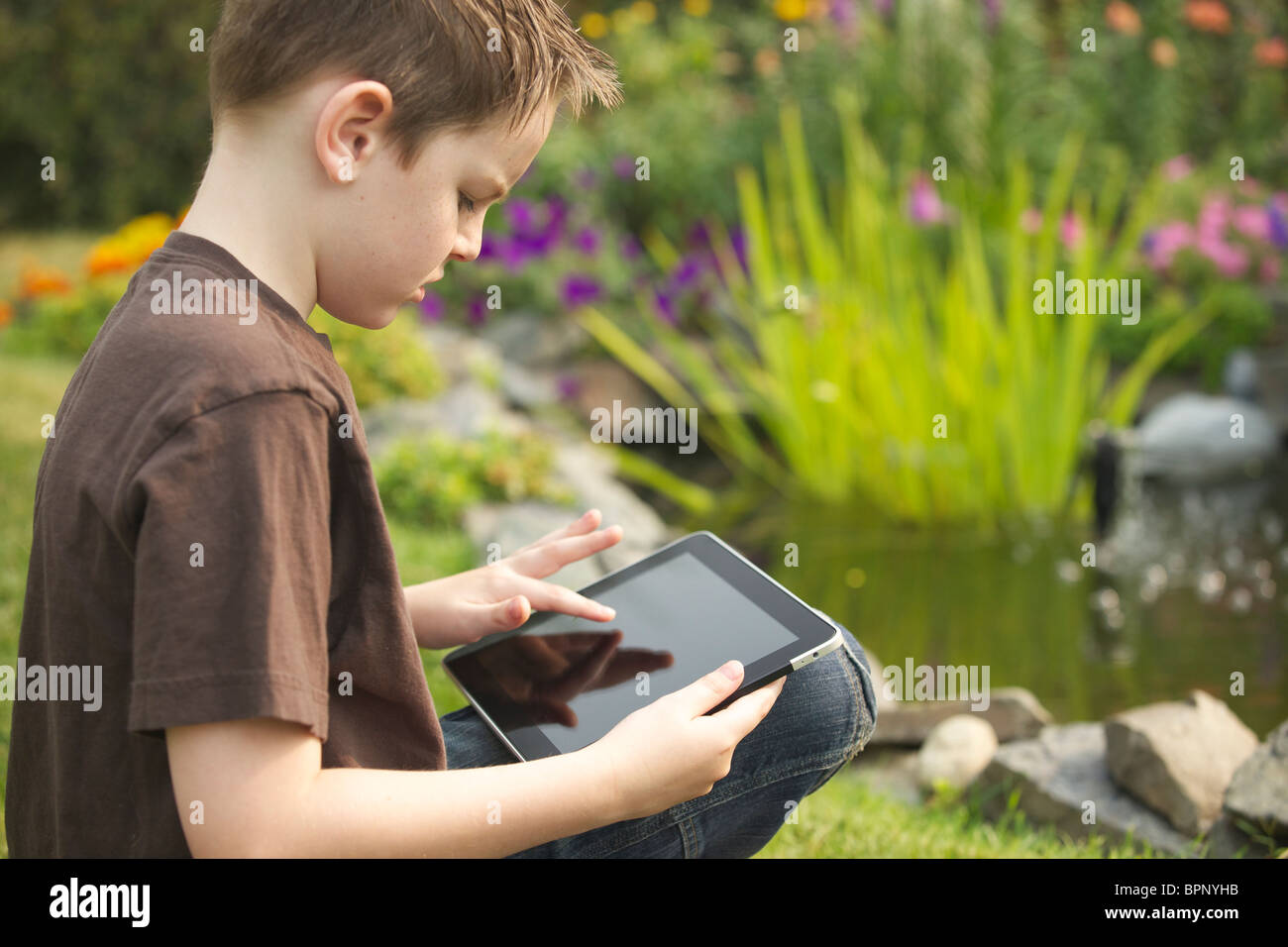 A 10 years old young boy using an iPad in the garden Stock Photo - Alamy