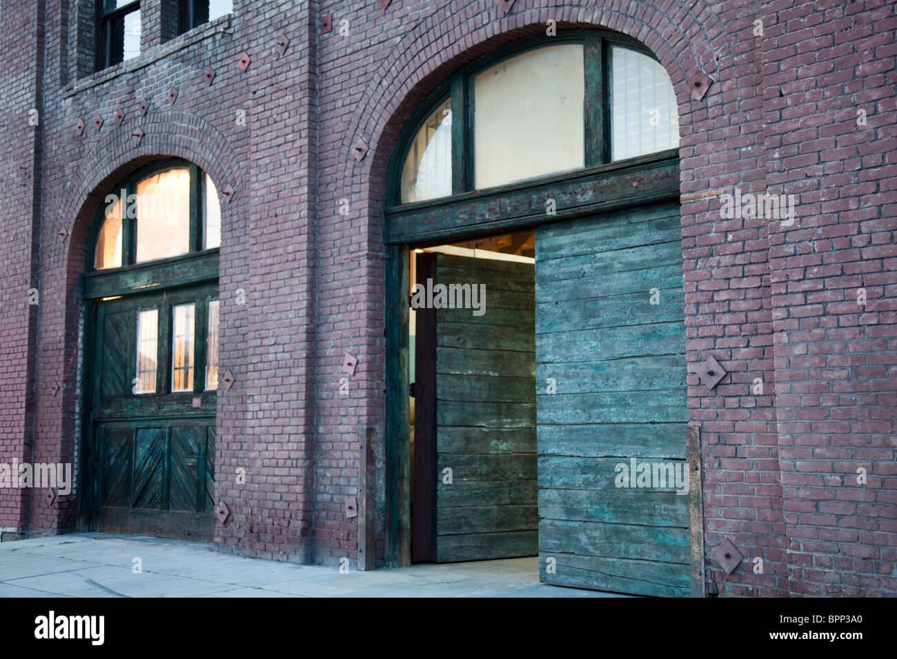 Old red brick building with large green doors Stock Photo - Alamy