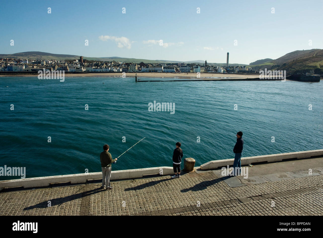 Man watching boy fishing off breakwater at Peel Harbour, Isle of Man ...
