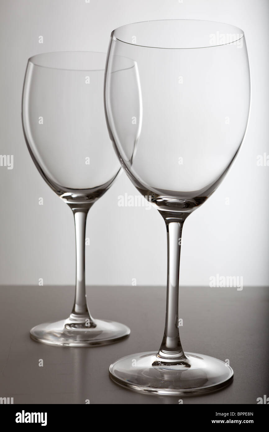 Two large empty wine glasses shot in the studio on a grey surface and ...