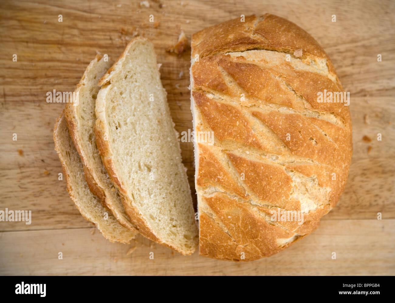 Round sliced crusty loaf of bread on wooden chopping board Stock Photo ...