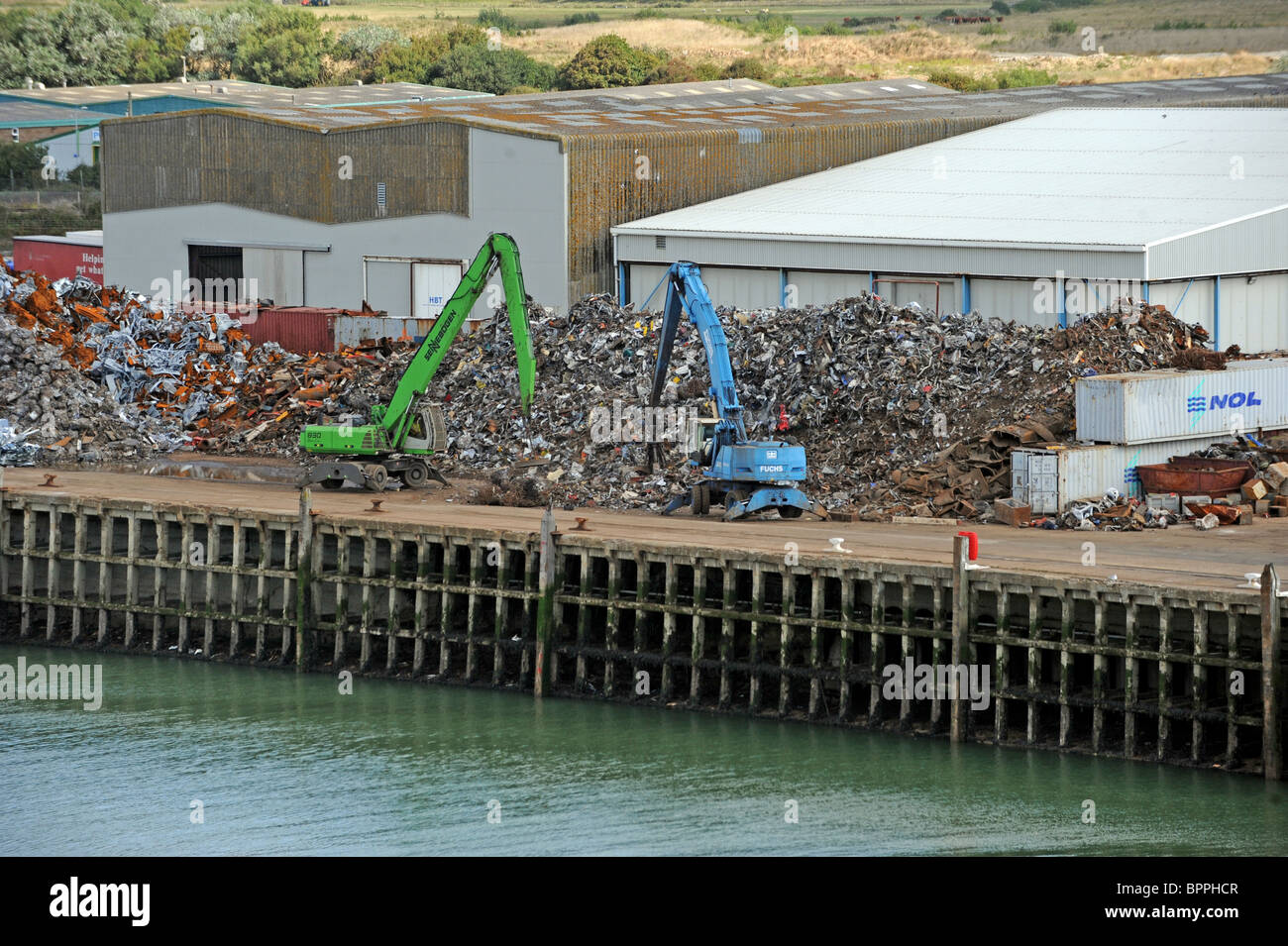 Mechanical loaders at work with piles of scrap metal on the dockside at ...