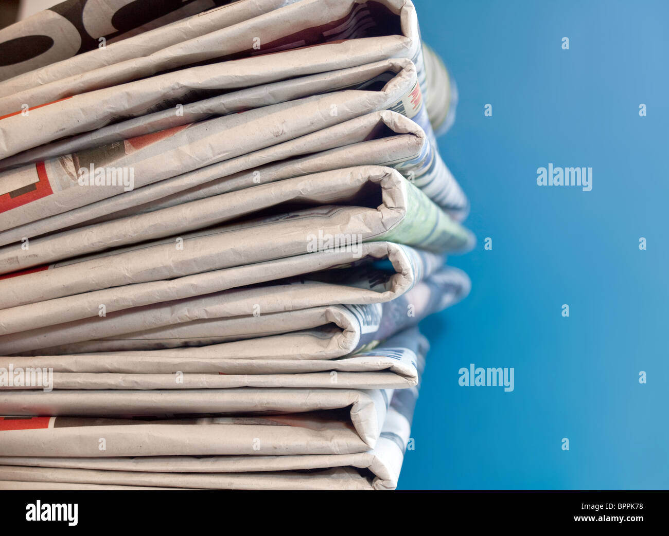 A stack of old newspapers with a blue background Stock Photo - Alamy
