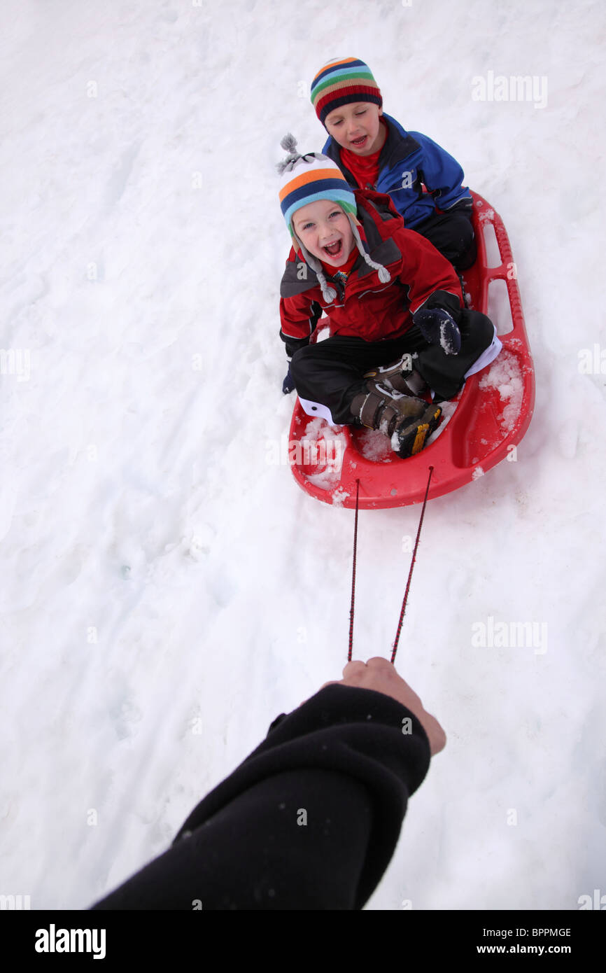 Pulling sled with two young boys Stock Photo - Alamy