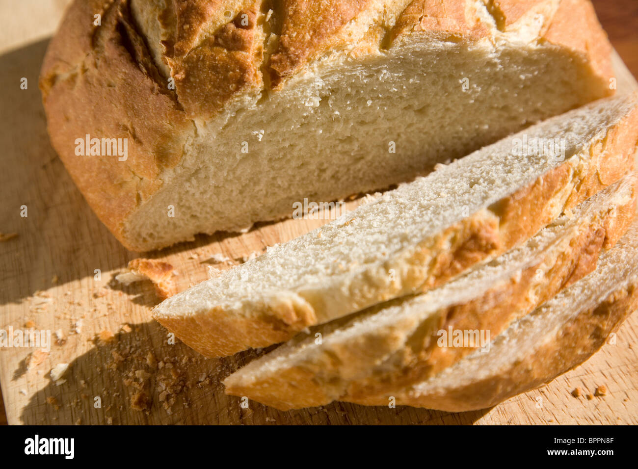 Round sliced crusty loaf of bread on wooden chopping board Stock Photo ...