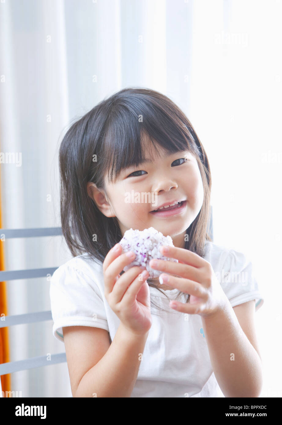 Girl eating a rice ball Stock Photo - Alamy