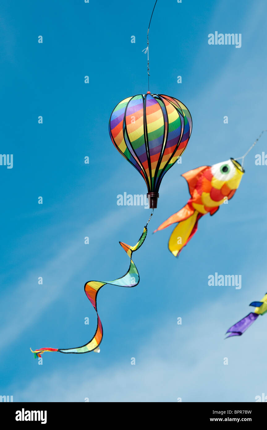 Colourful twirling wind decorations or wind spinners against a blue sky ...