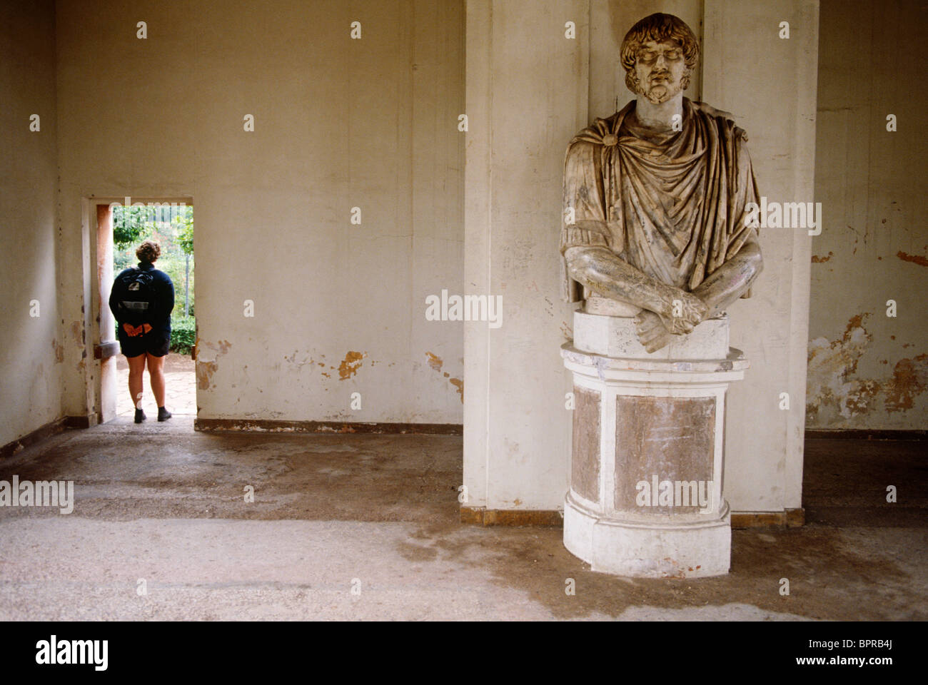 Tourist stands in doorway by unknown bust of Roman figure at Rome's ...