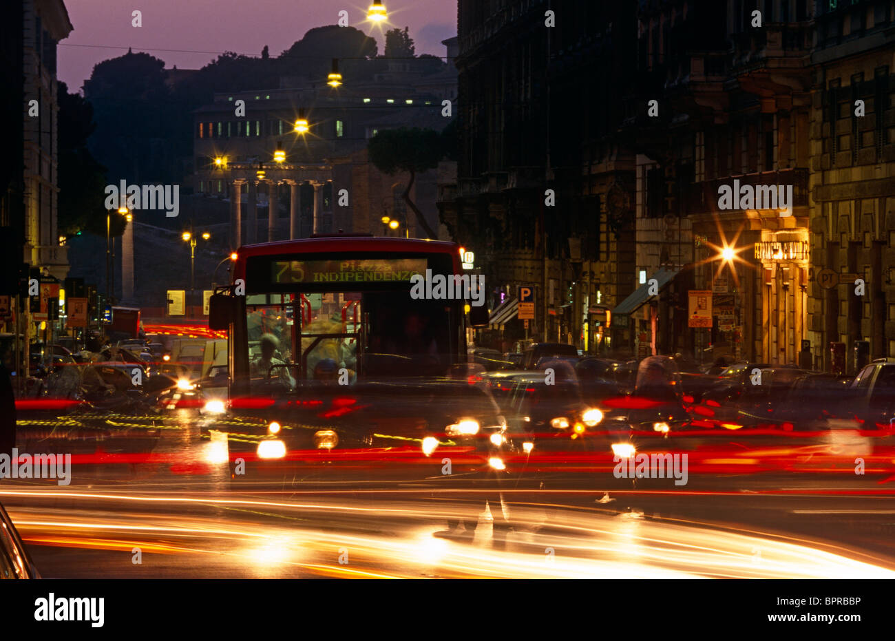 Blurred traffic on Rome's Via Cavour street with Roman Forum columns in ...
