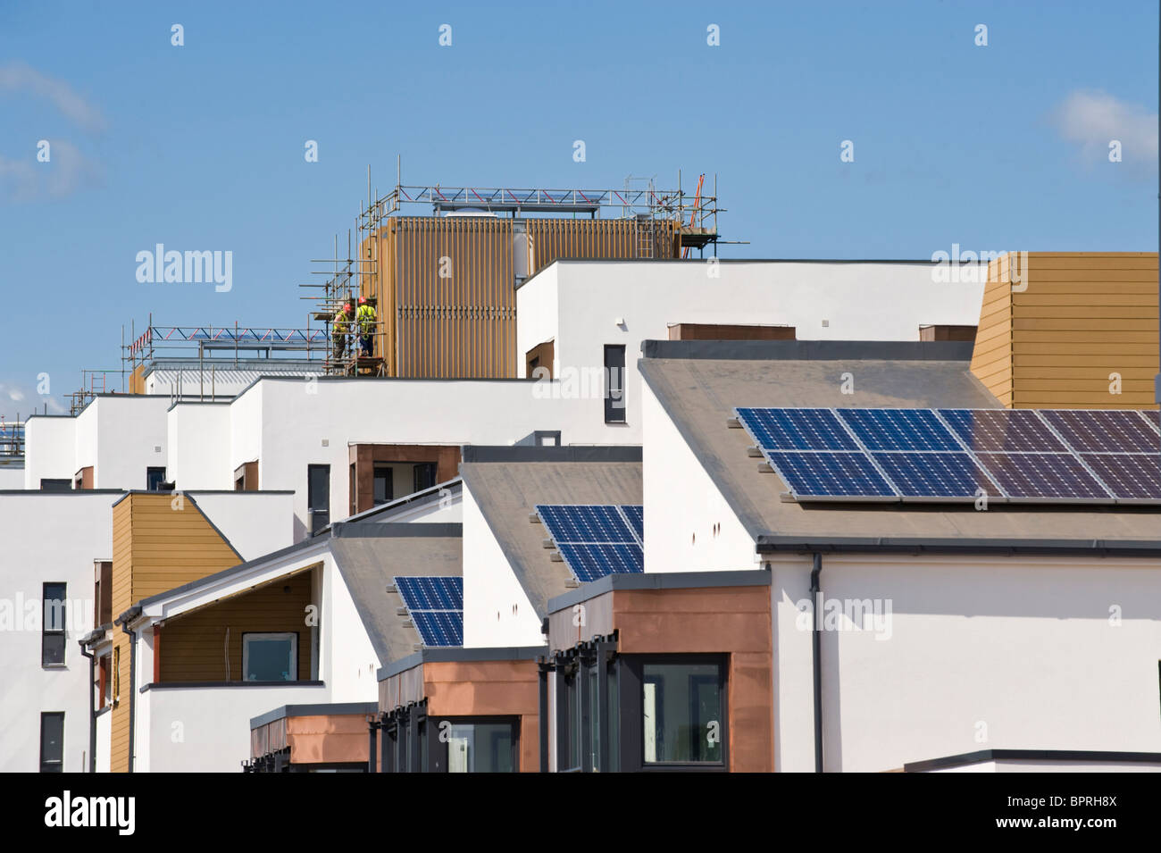 Modern apartments with solar panels on roof under construction on brown ...