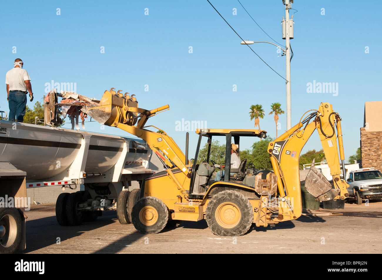 A backhoe is being used to remove debris from the demolition of an old ...