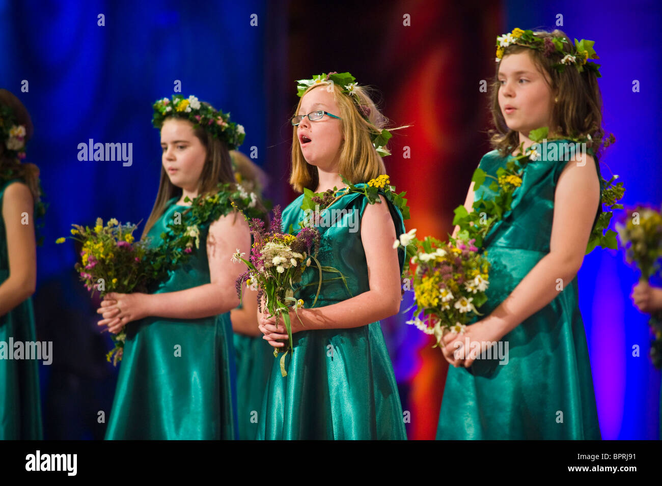 Young flower girls wearing garlands and carrying bouquets of flowers on ...