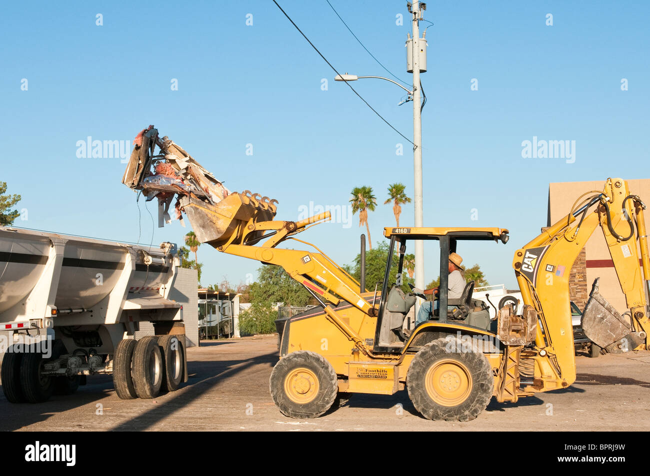 A backhoe is being used to remove debris from the demolition of an old ...