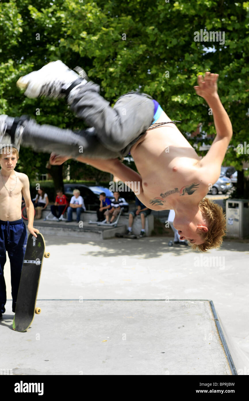 Teenage boy wearing roller-blades performs daredevil stunts in front of ...