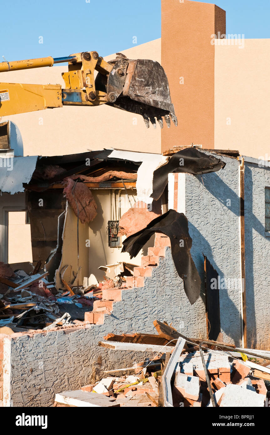 A backhoe is being used to knock down an old commercial building and ...
