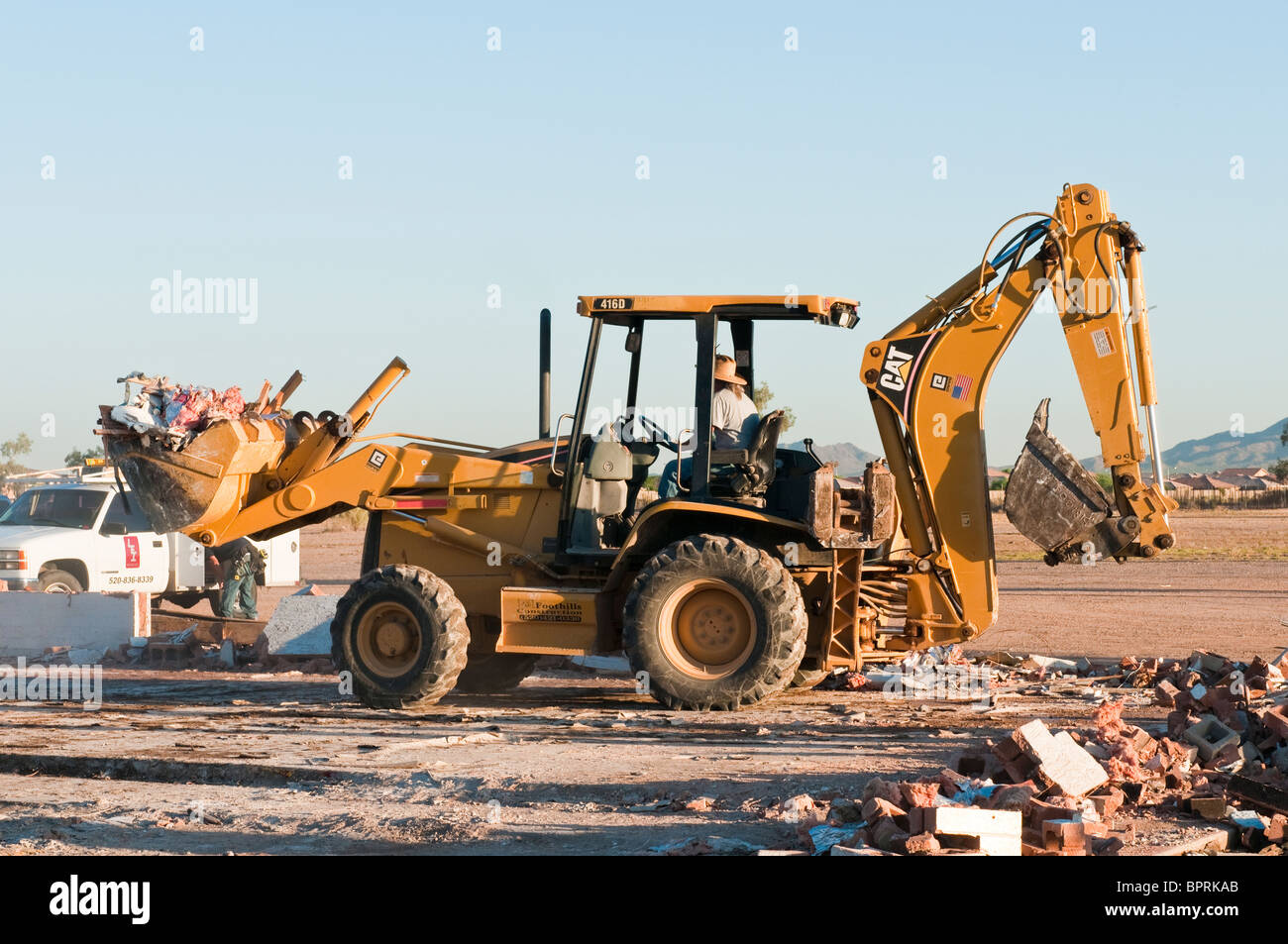 A backhoe is being used to remove debris from the demolition of an old ...