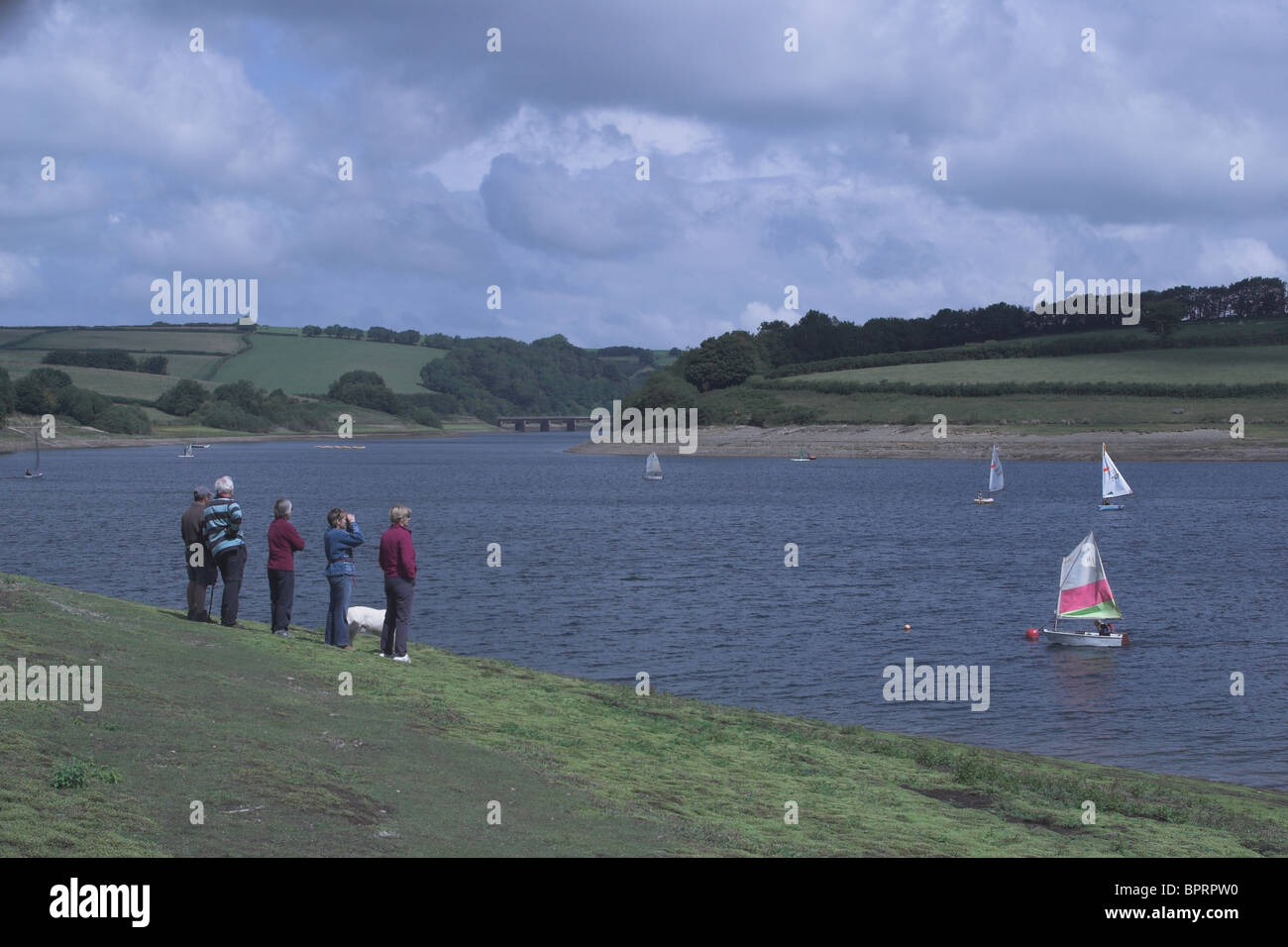 Spectators watching dinghy sailing from shore of Wimbleball Lake ...