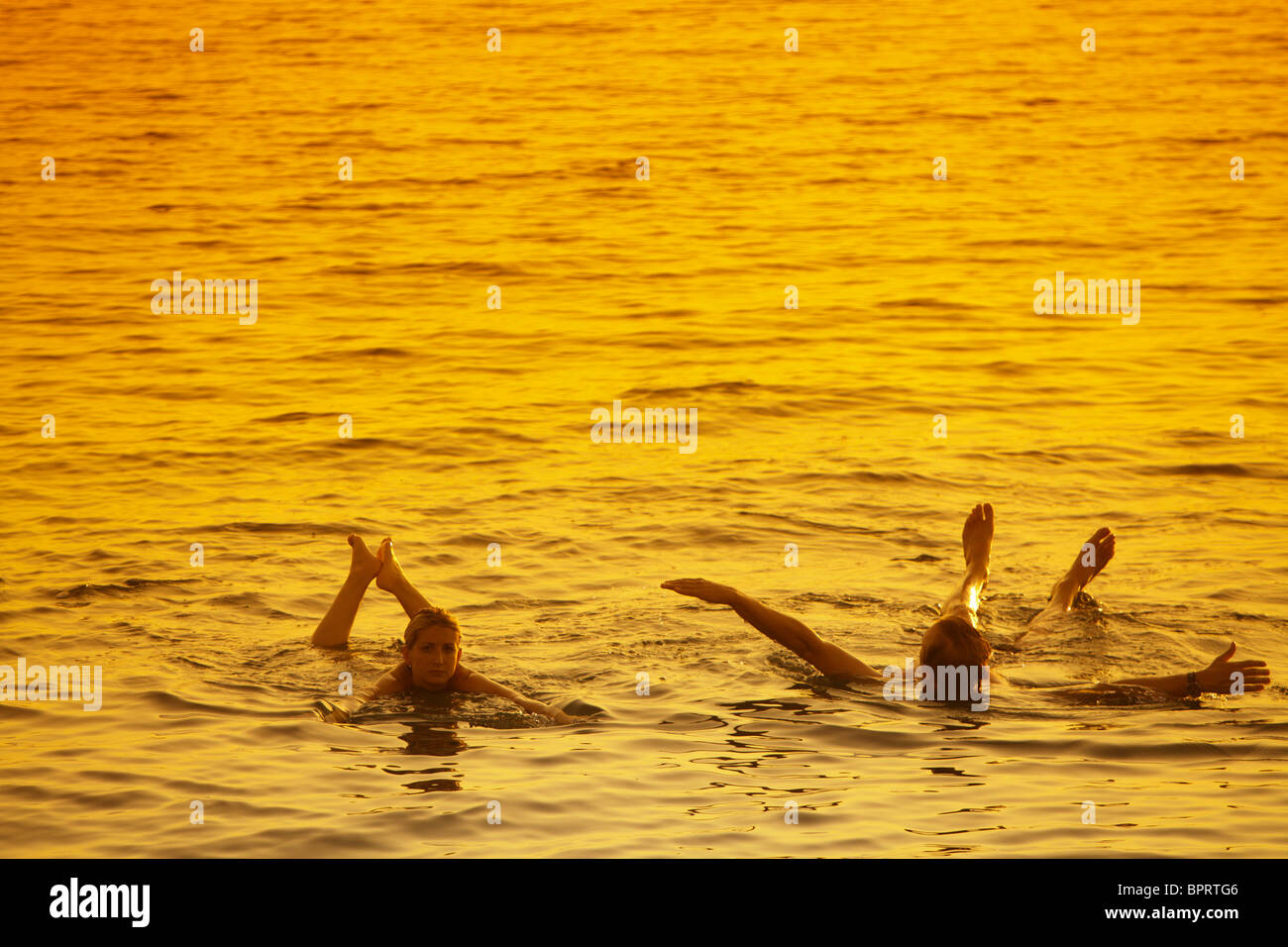 People floating in the dead sea at sunset, Jordan Stock Photo - Alamy