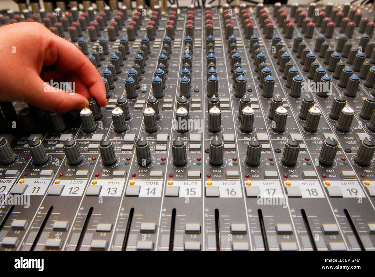 Man adjusting sound levels in mixing suite at a music resource centre ...