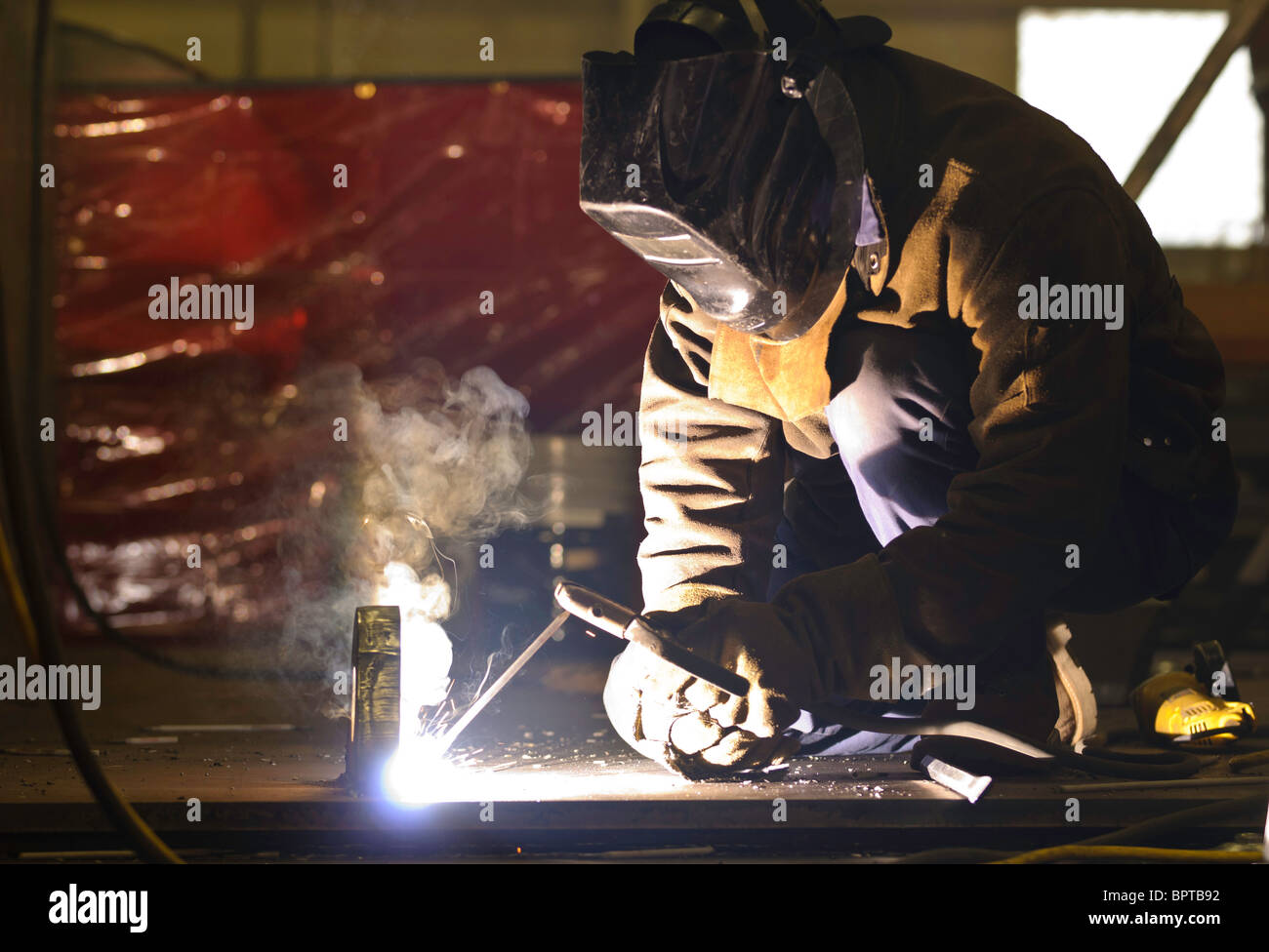 medium shot of engineer welding steel - showing safety gear, arc welder ...