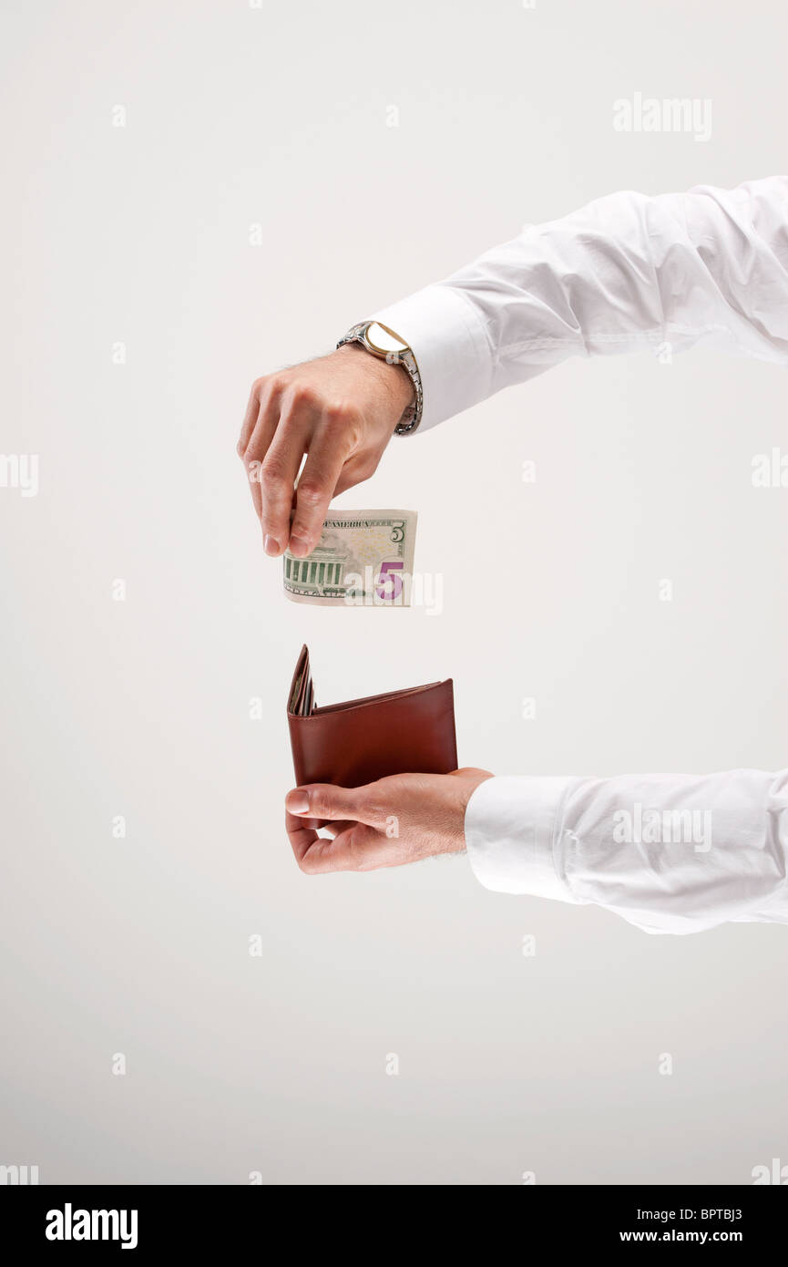Man puts five dollars into wallet Stock Photo - Alamy