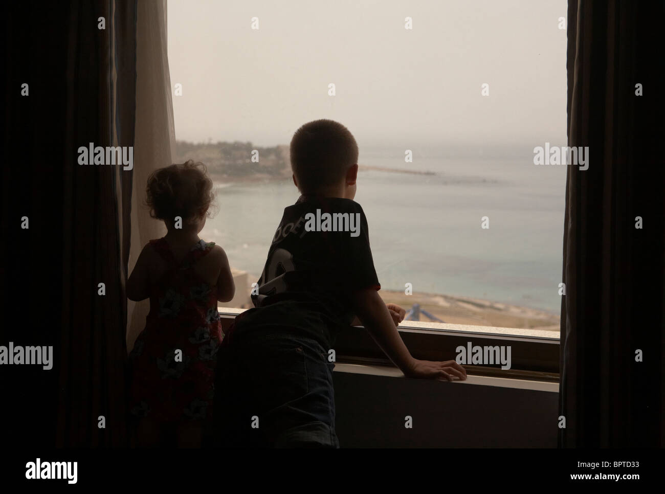 Two kids staring at a window toward a sea shore Stock Photo - Alamy