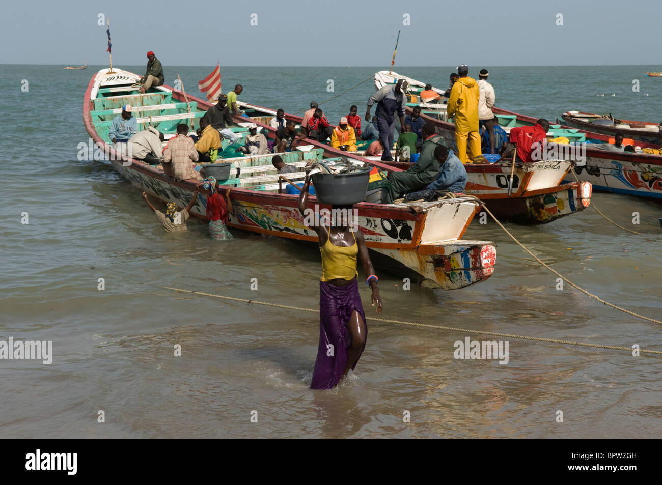 people off-load fish from fishing pirogues at the fish market, Tanji ...