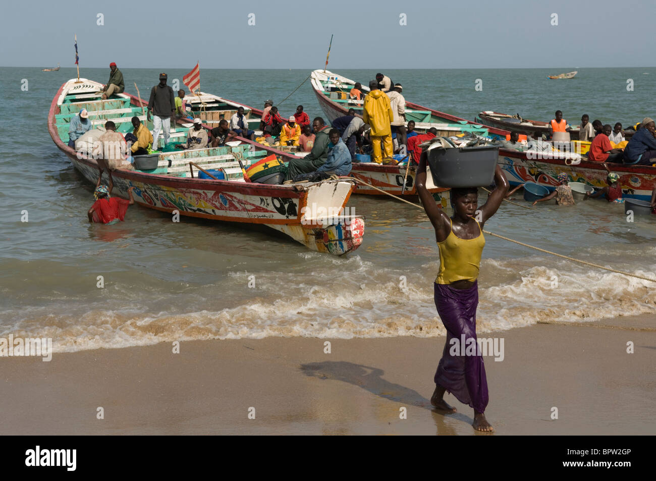 people off-load fish from fishing pirogues at the fish market, Tanji ...