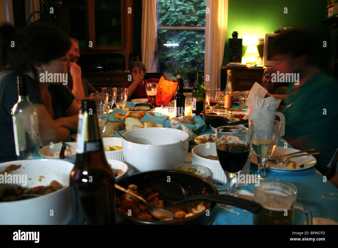 friends talking and laughing around a dinner table full of tapas and ...