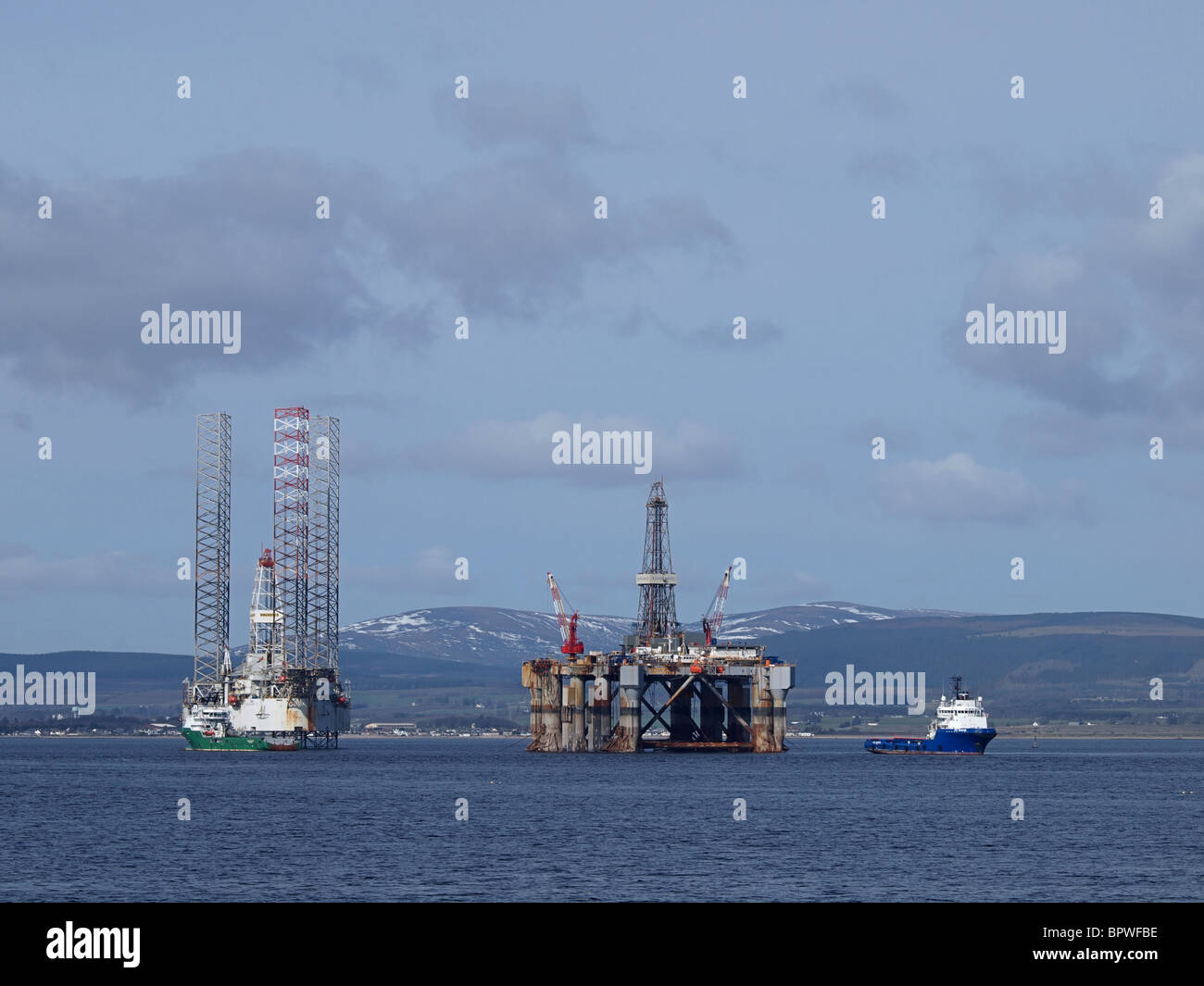 The anchors of a semi-submersible oil rig are lifted by two anchor ...