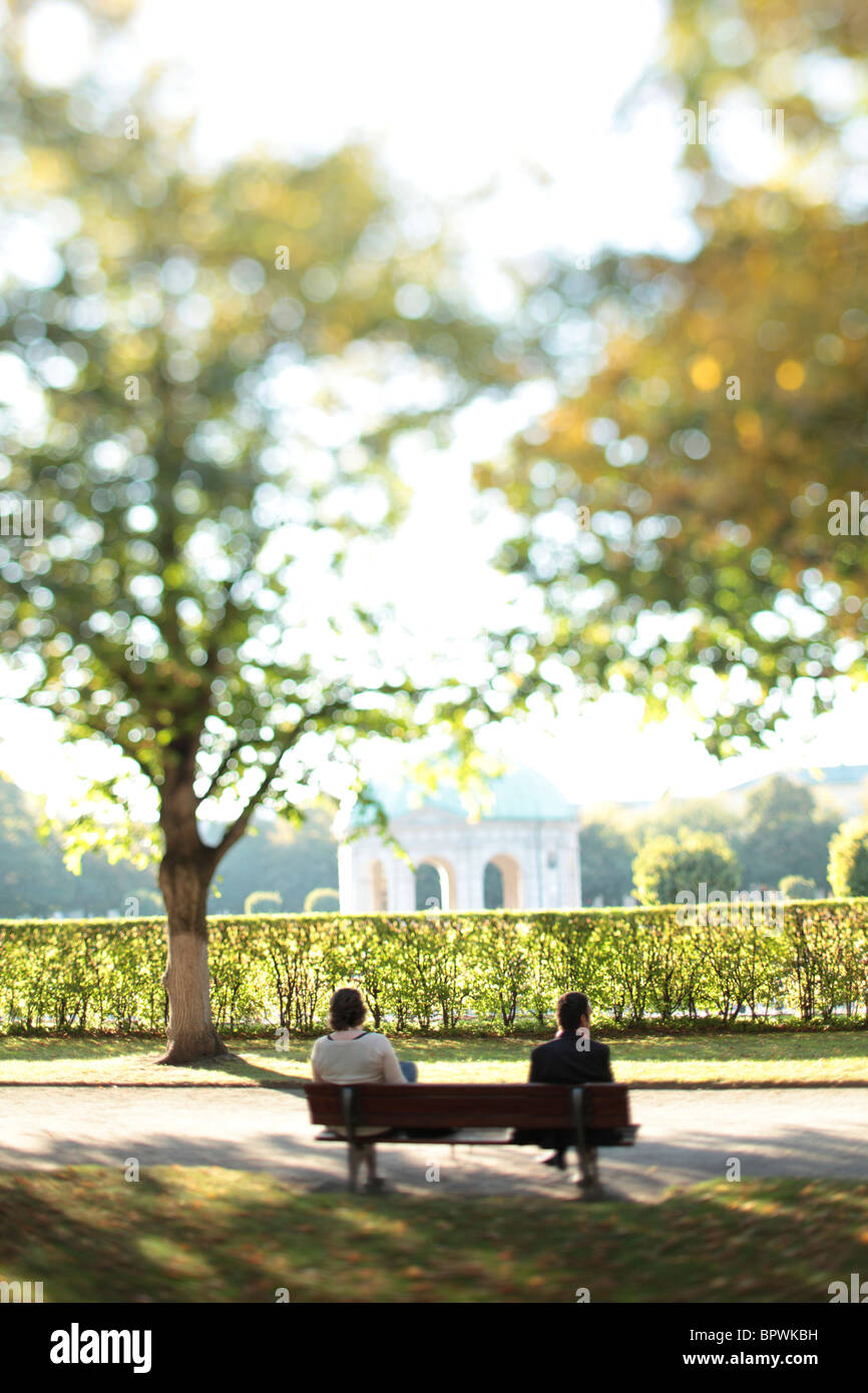 Rear view of a man and woman sitting on a bench in Munich Stock Photo ...