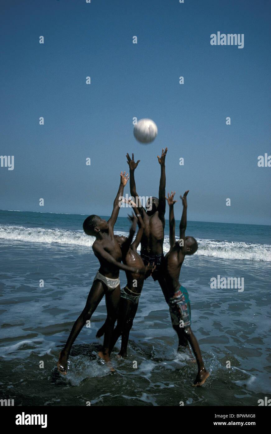 Four young boys playing football in the surf off Gambia, West Africa ...