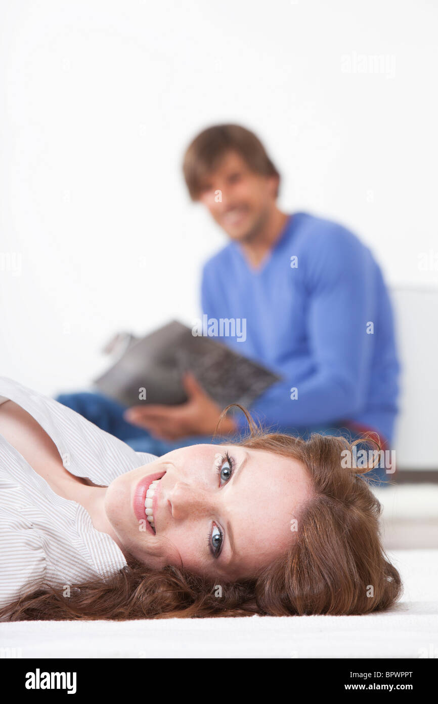 Woman lying on rug, man reading Stock Photo - Alamy