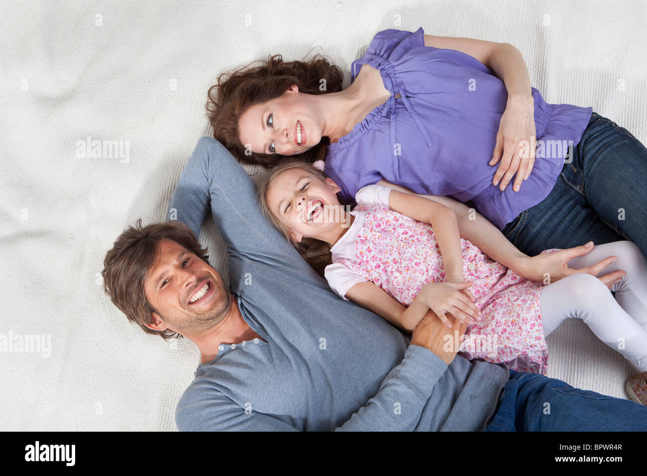 Happy family lying on rug Stock Photo - Alamy