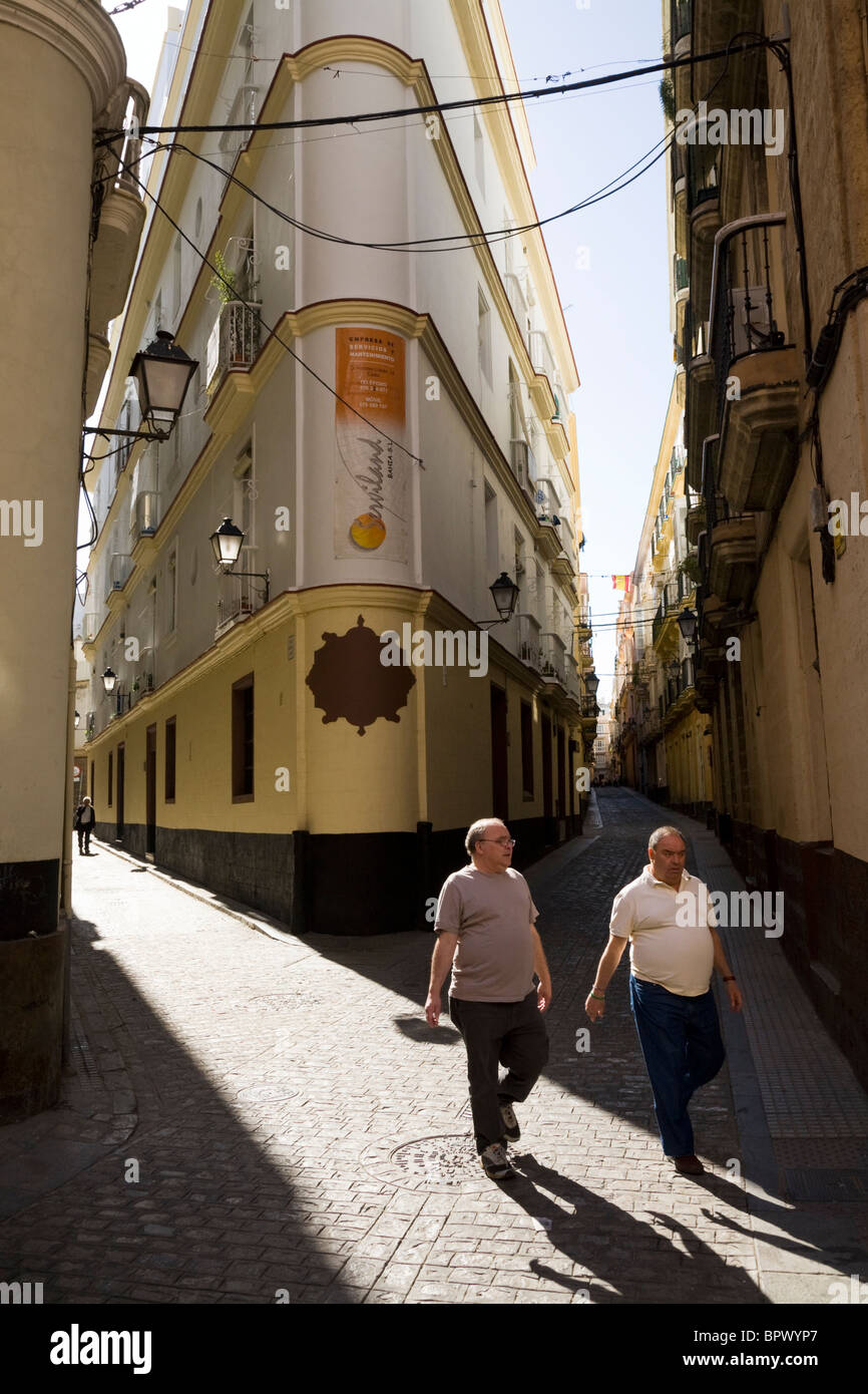 Men walk on typical Spanish cobbled back street / streets / road along ...