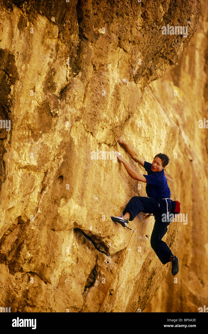 Male rock-climber using balance while climbing reddish brown rock Stock ...