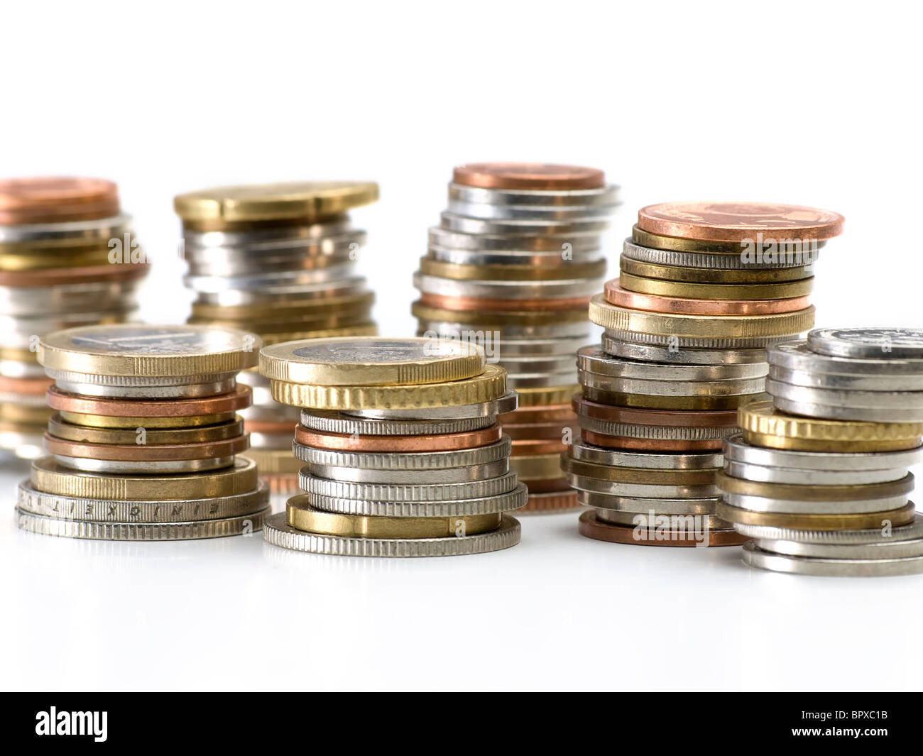 stacks of money coins of various currencies over white background ...