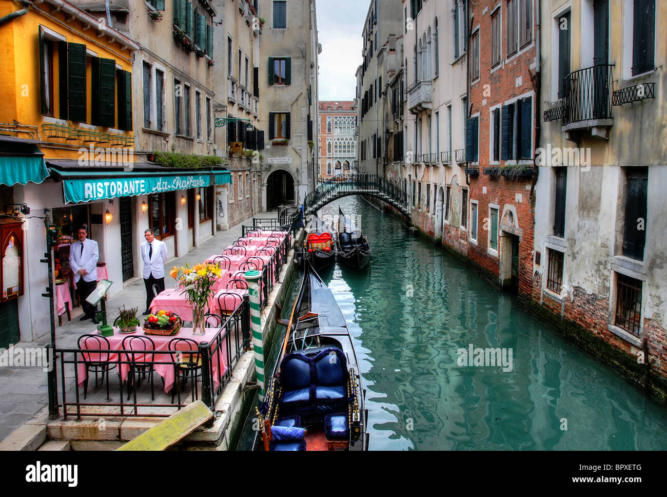 Small romantic restaurant on venetian canal at evening in Venice, Italy ...