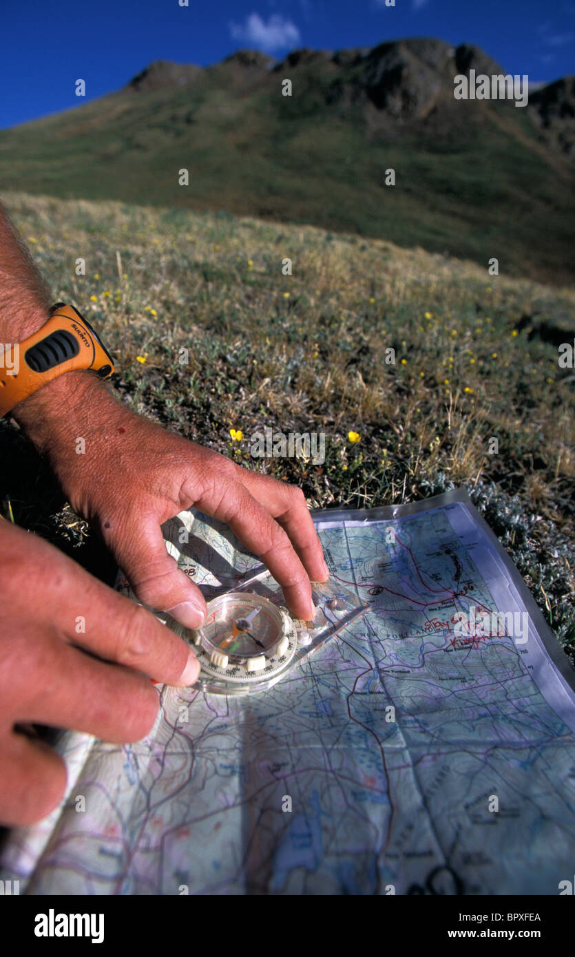 Man uses compass and topographic map to navigate in the mountains above ...