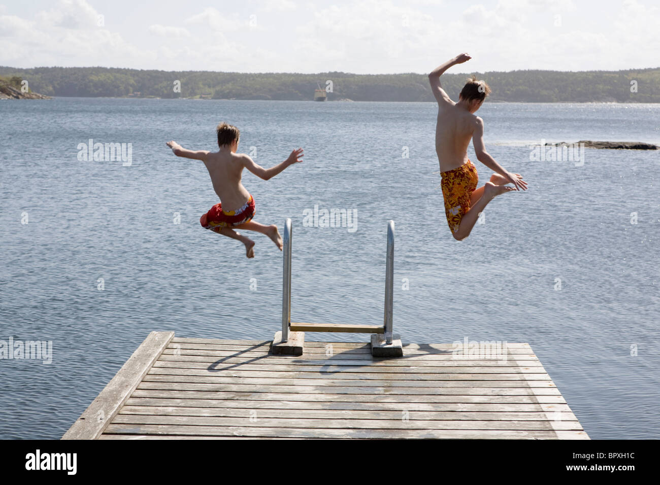 Two boys are jumping into the wather Stock Photo - Alamy