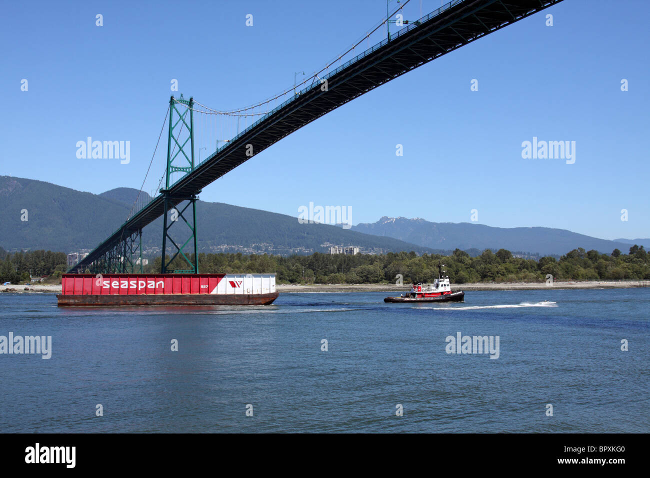 A tugboat pulls a barge under Vancouver's Lions Gate Bridge Stock Photo ...