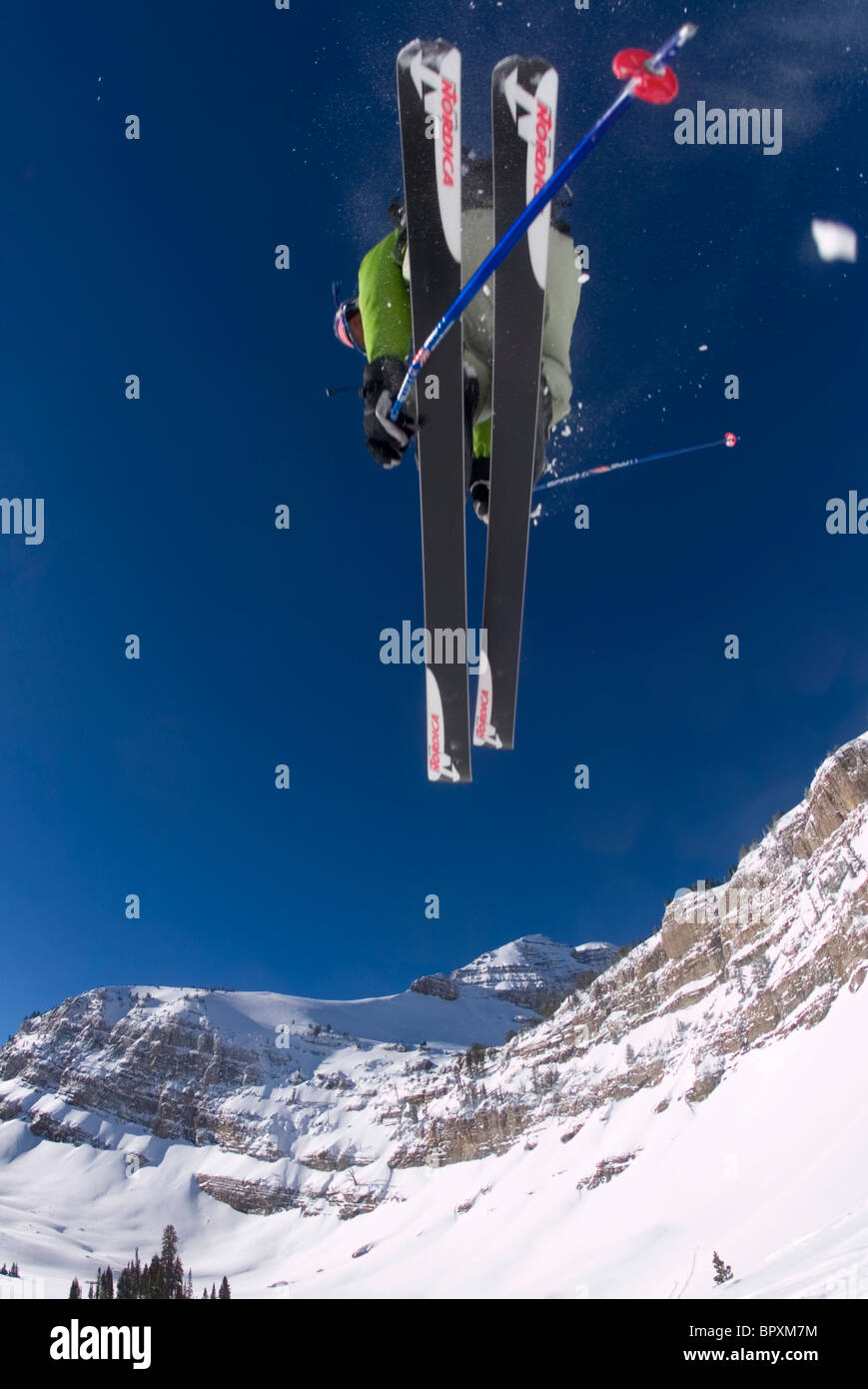 Man jumping over camera on skis with mountains behind Stock Photo - Alamy