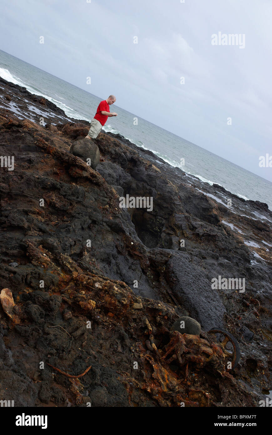 A man stands on the shores of Glass Beach, Hawaii, observing the ...