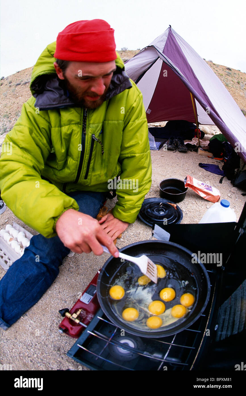 Man cooking nine eggs in front of his tent Stock Photo - Alamy