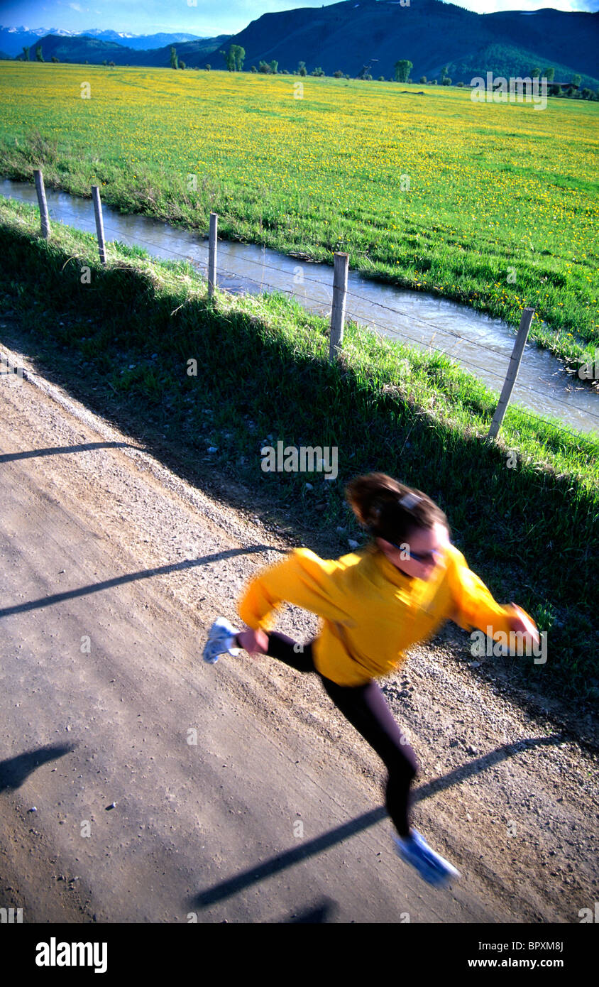 Woman running down dirt road Stock Photo - Alamy