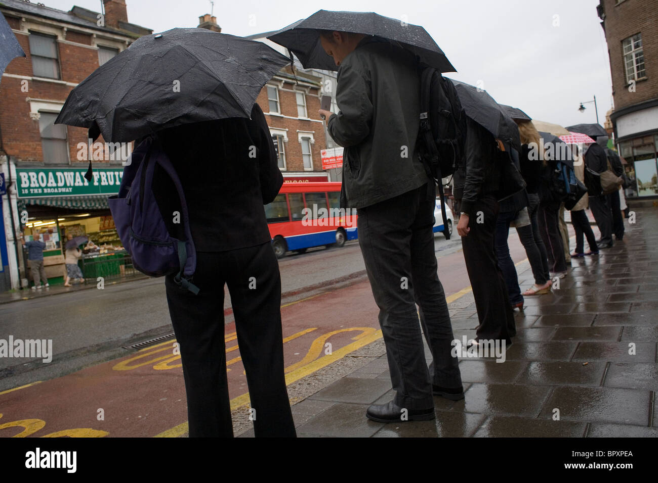 People queue in the rain for a bus on a wet Tuesday morning at the ...