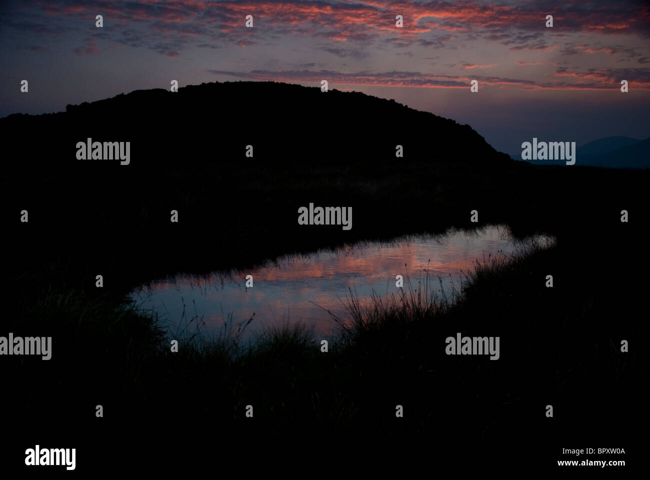 Sunset and clouds reflected in tarn on Lingmell, Lake District, Cumbria ...