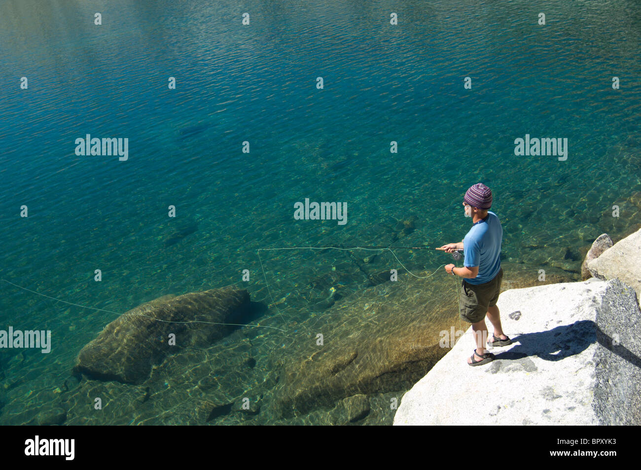 Solo man fly fishing above blue lake Stock Photo - Alamy