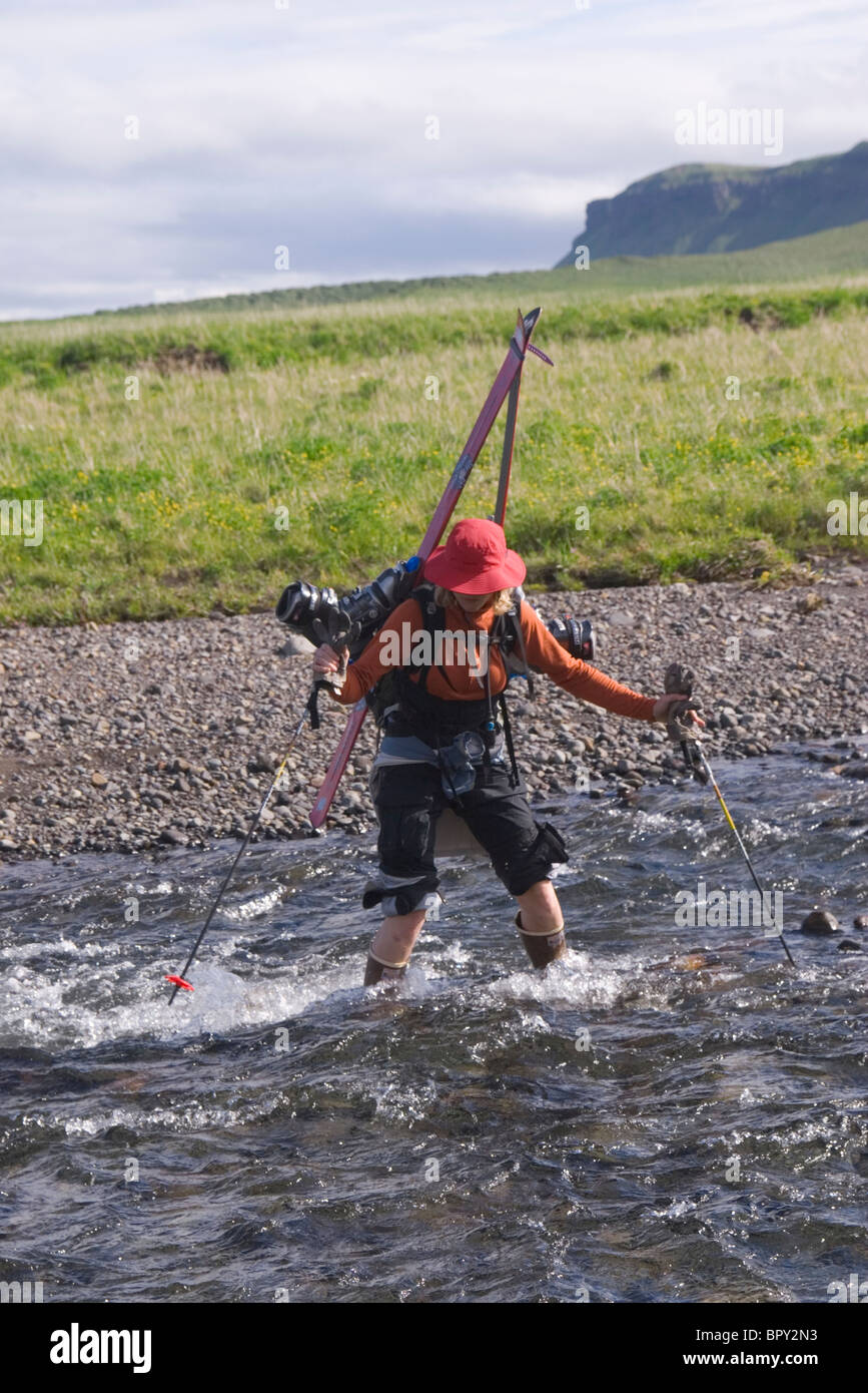 A woman skier crossing a river on Umnak Island in the Aleutian Islands ...