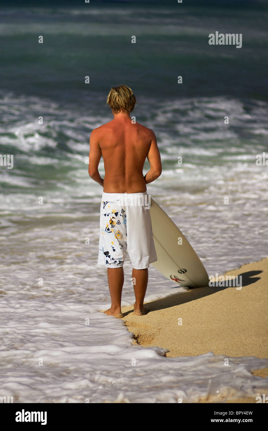 Young surfer with surfboard in Pacific Ocean on the North Shore of Oahu ...